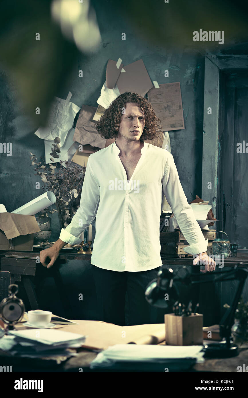 Writer at work. Handsome young writer standing near the table and ...