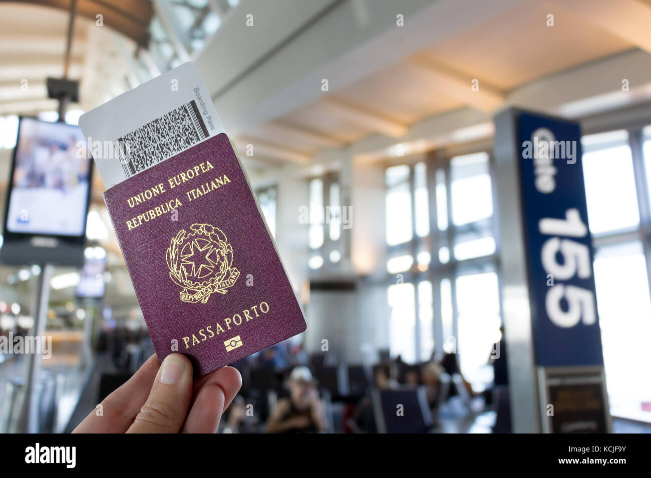 Hand holding an Italian passport with boarding pass inside at the ...