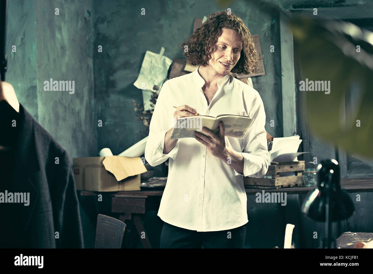 Writer at work. Handsome young writer standing near the table and ...