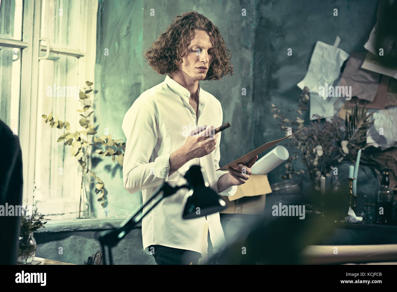 Writer at work. Handsome young writer standing near the table and ...