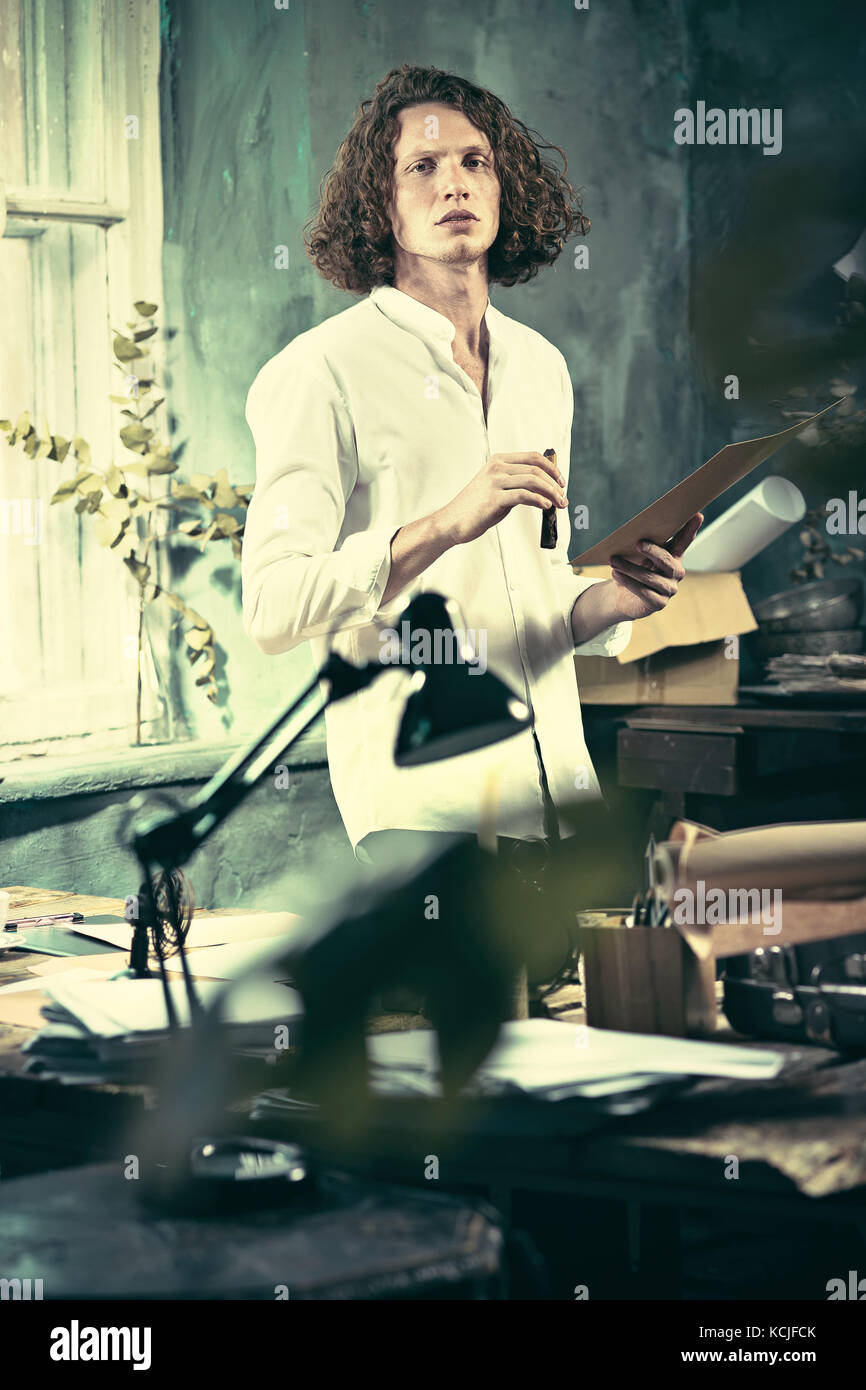 Writer at work. Handsome young writer standing near the table and ...