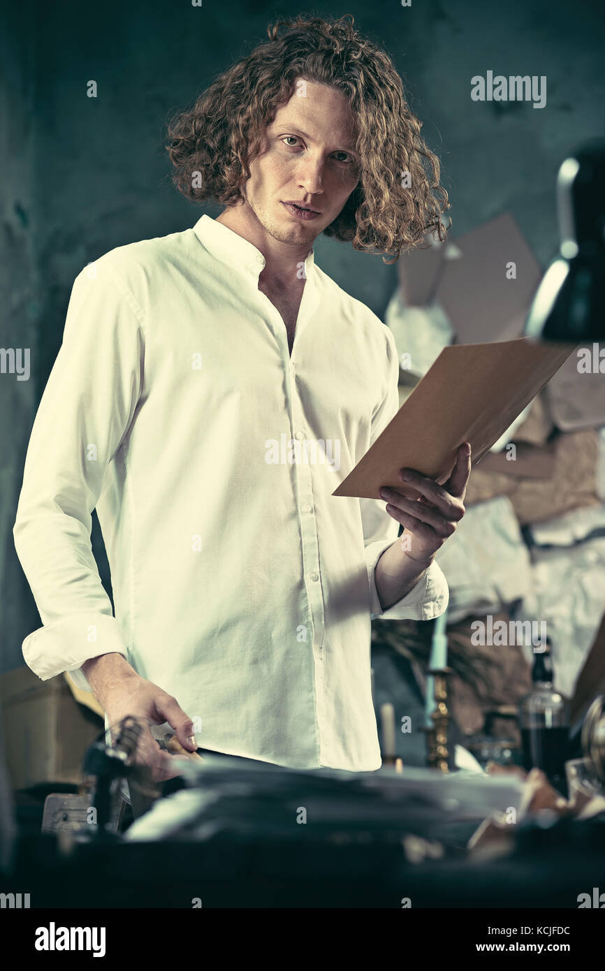 Writer at work. Handsome young writer standing near the table and ...