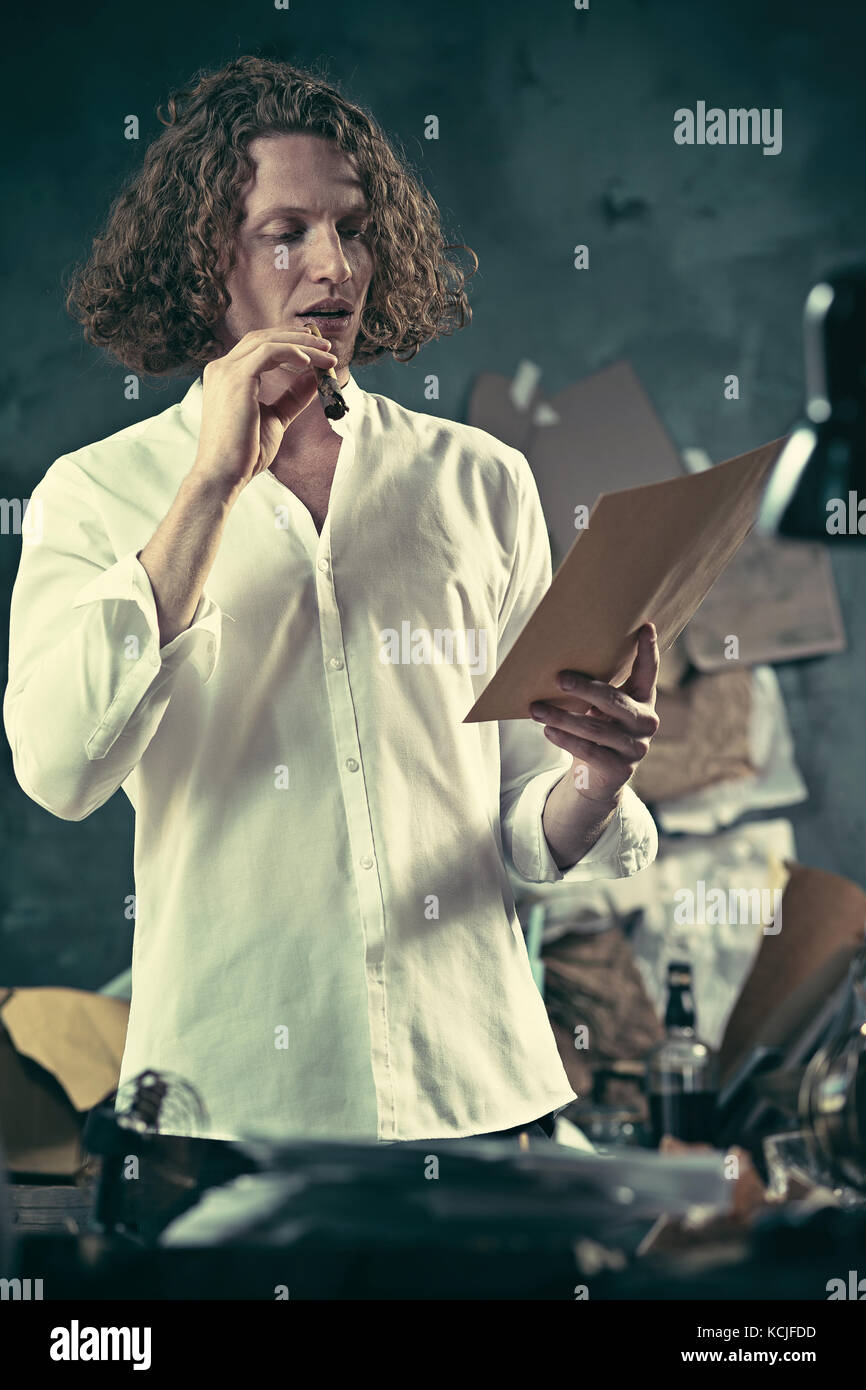 Writer at work. Handsome young writer standing near the table and ...