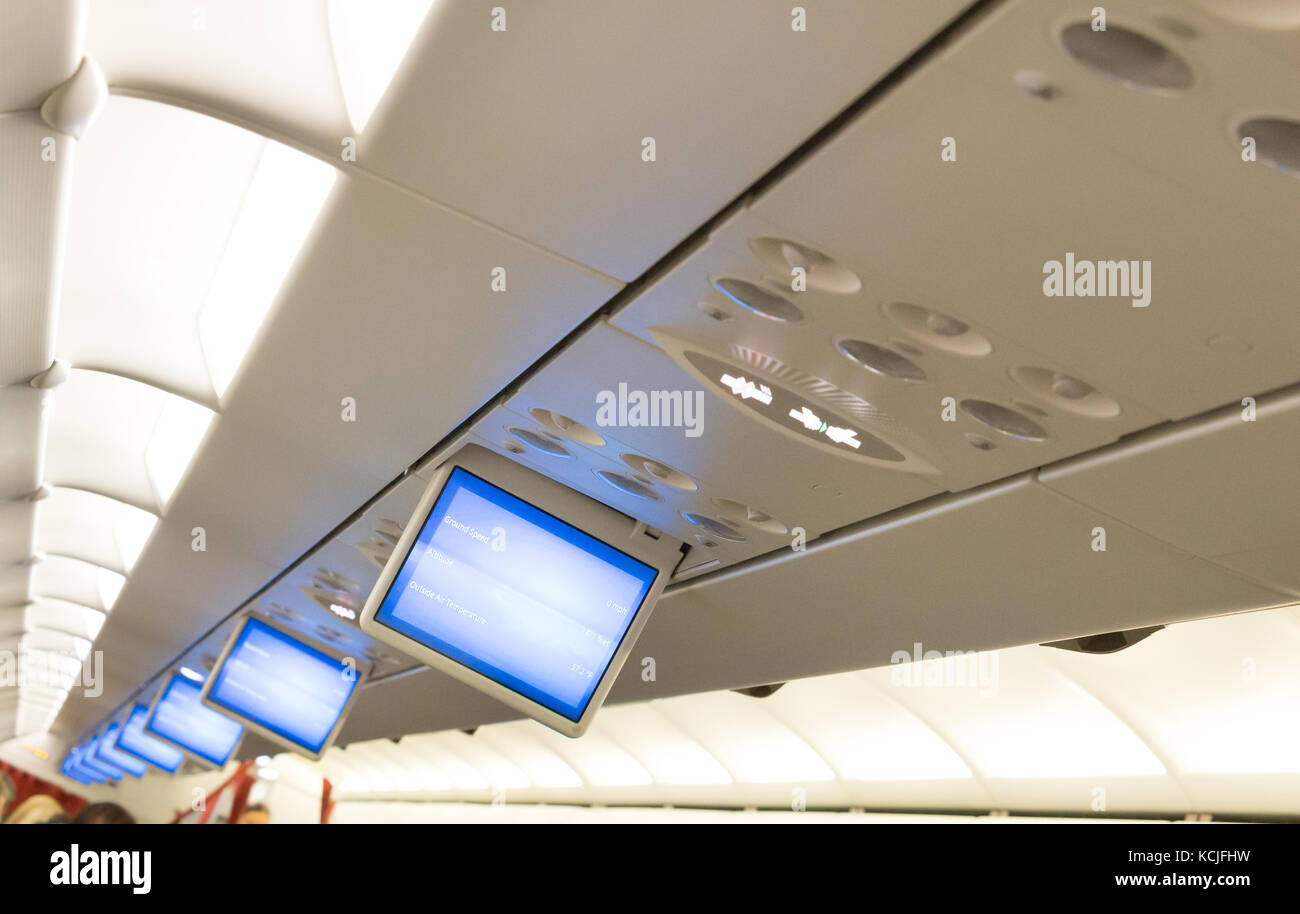 An in-flight monitors are attached on the ceiling in the economy class ...