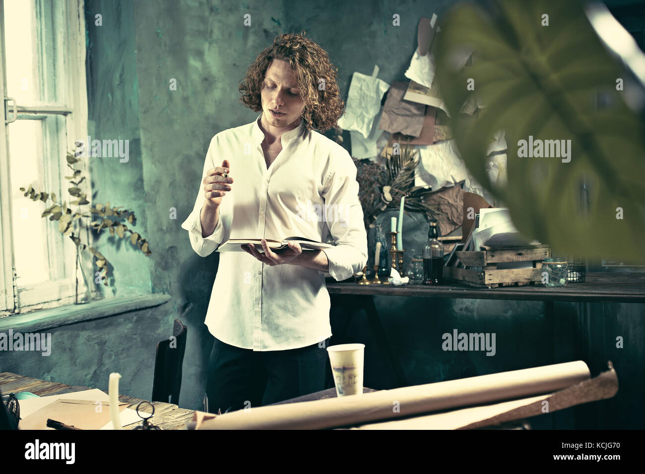 Writer at work. Handsome young writer standing near the table and ...