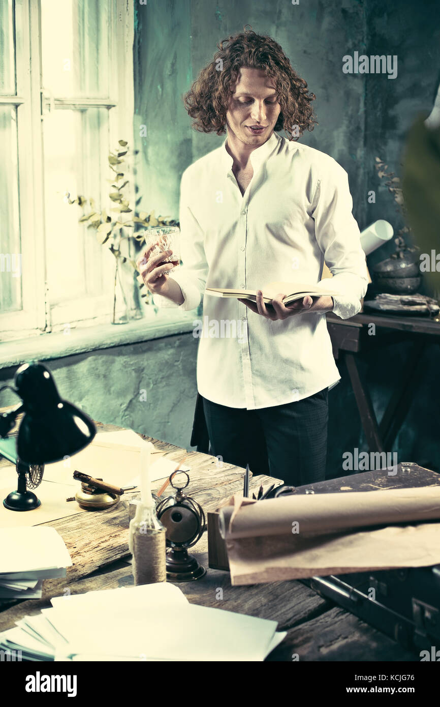 Writer at work. Handsome young writer standing near the table and ...