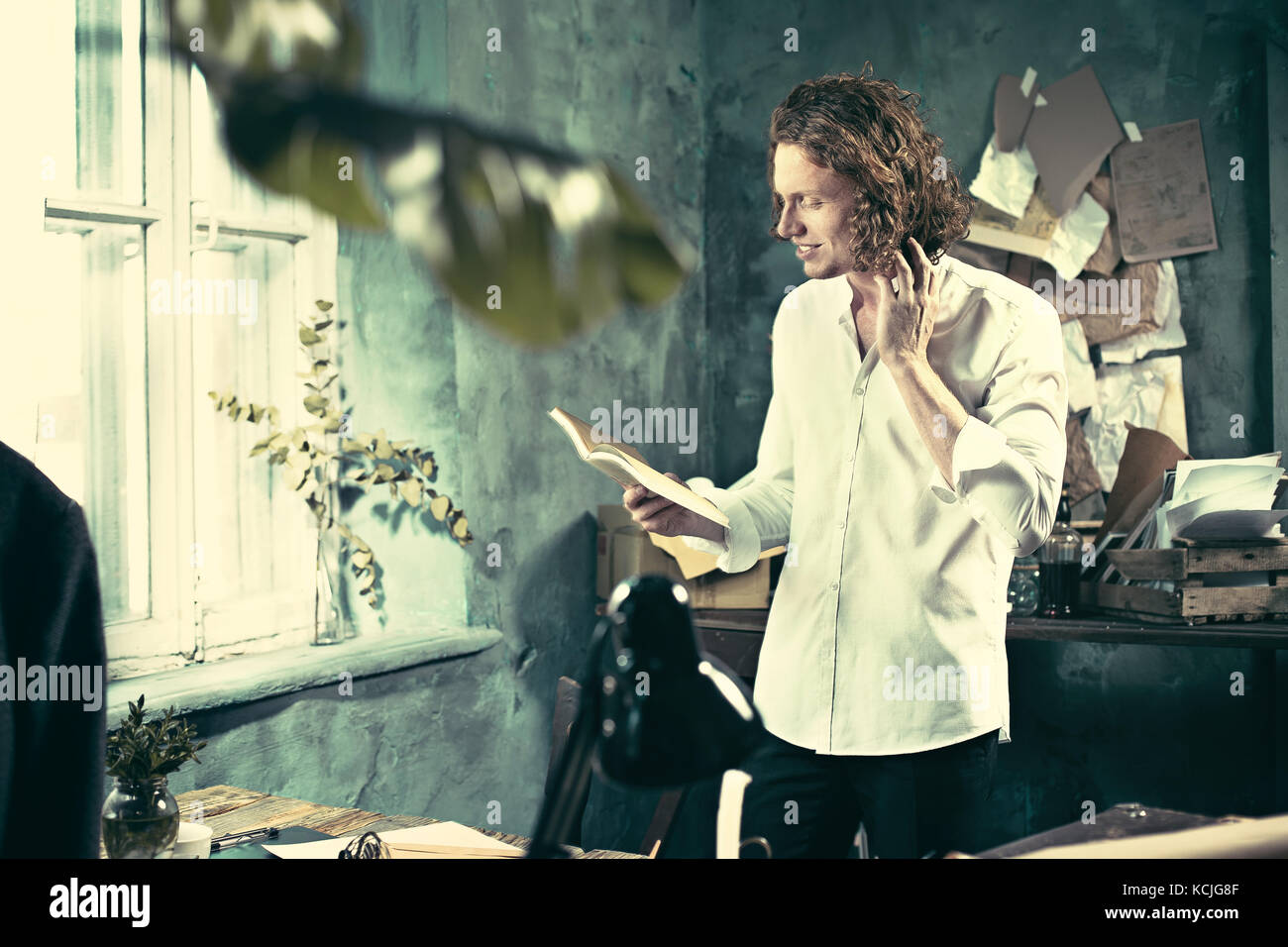 Writer at work. Handsome young writer standing near the table and ...