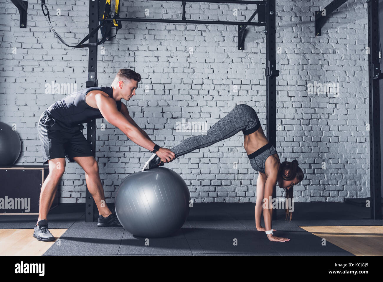 trainer helping woman work out Stock Photo - Alamy
