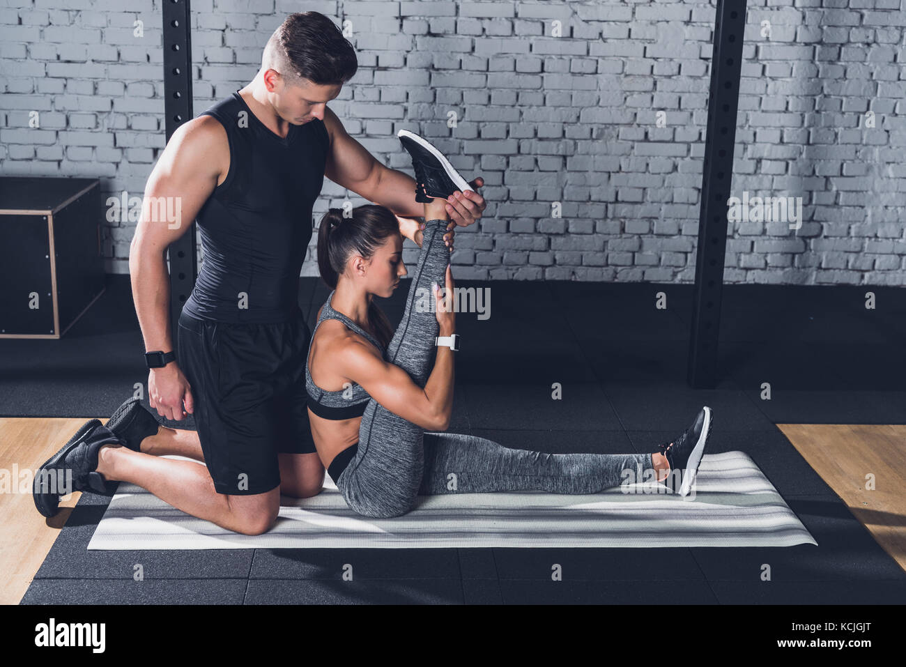 trainer helping woman to stretch Stock Photo - Alamy