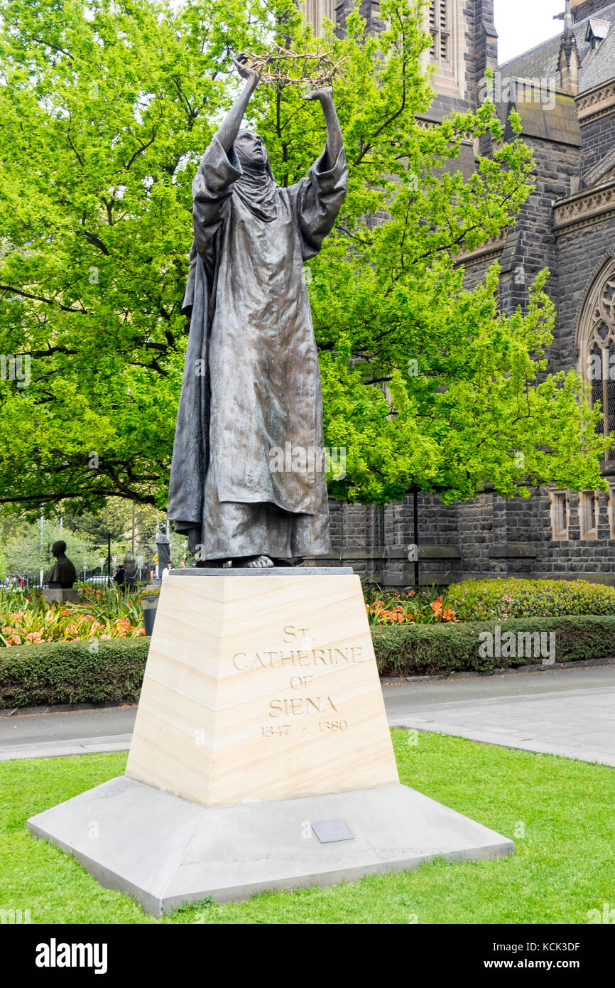 Bronze statue of St Catherine of Siena holding up a crown of thorns ...