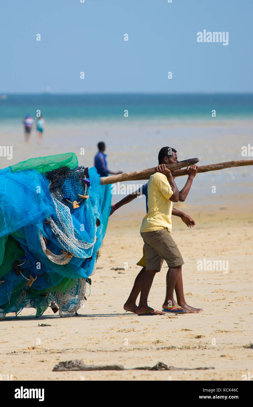 Fisherman carry fishing nets back from boat, Ifaty Beach, Madagascar ...
