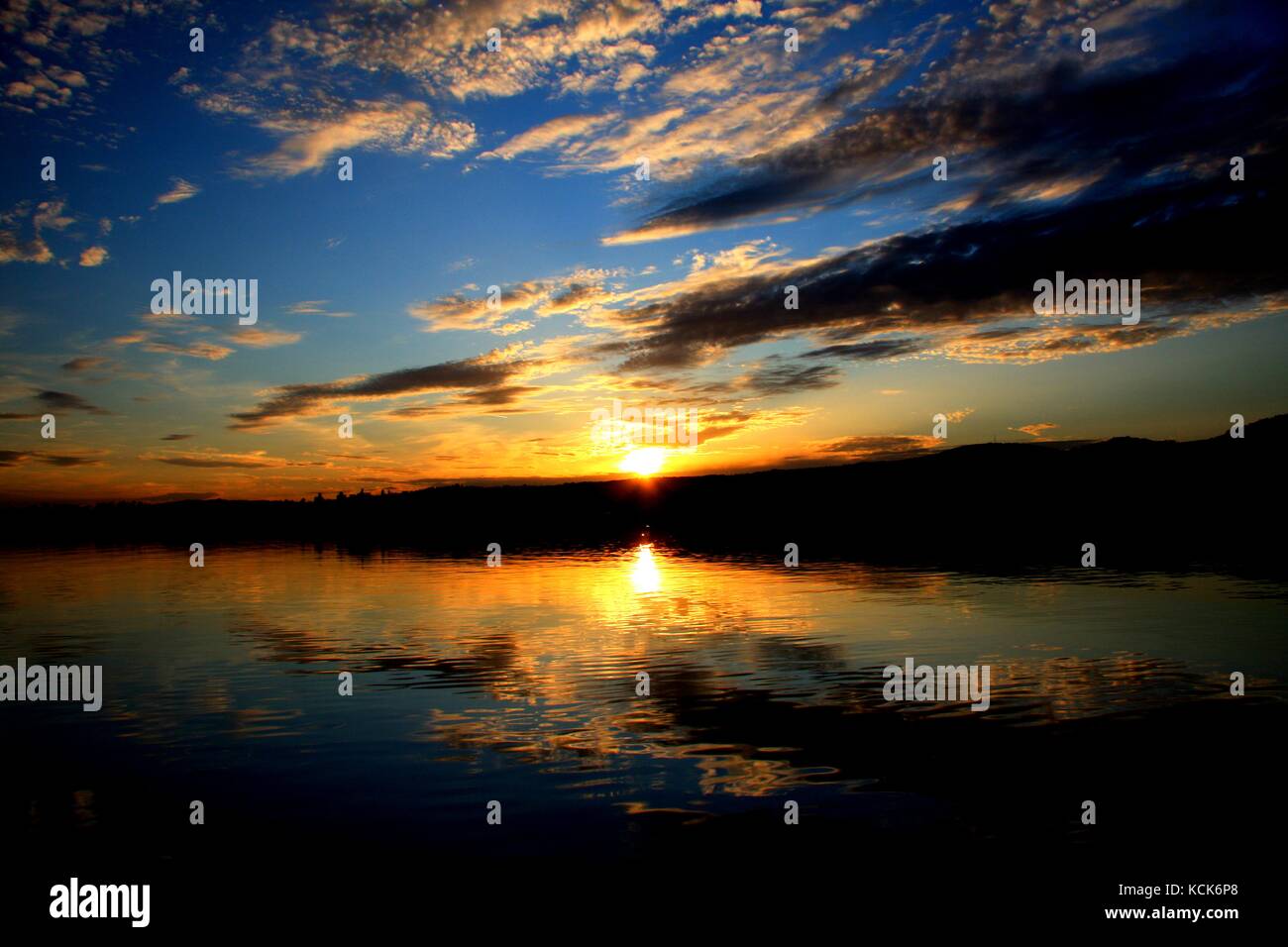 Mirror. Summer sunset time. Sun goes down behind the mountain ...