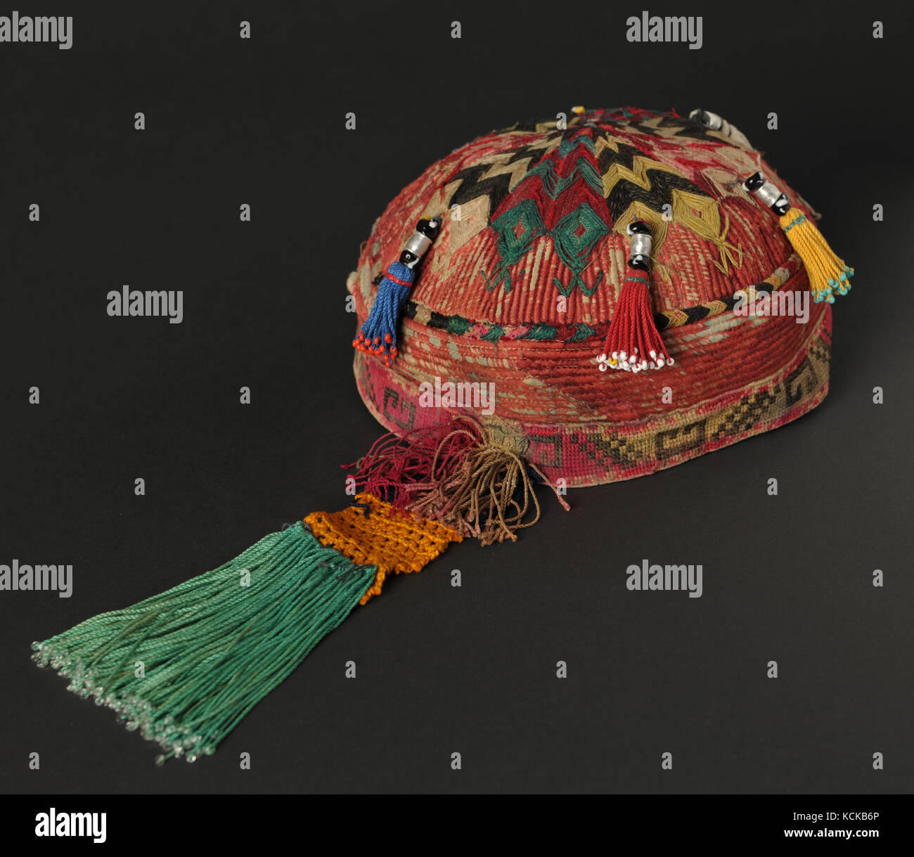 colorful traditional asian skullcap hat with pigtails on a dark ...