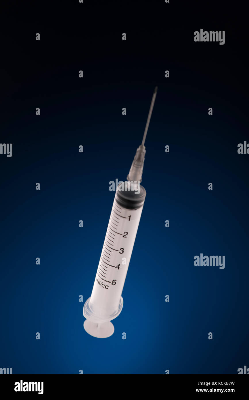 one medical syringe in an upright position on a dark blue background ...