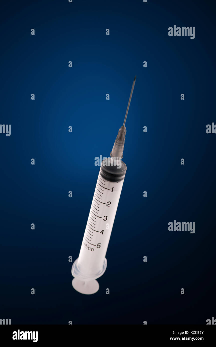 one medical syringe in an upright position on a dark blue background ...