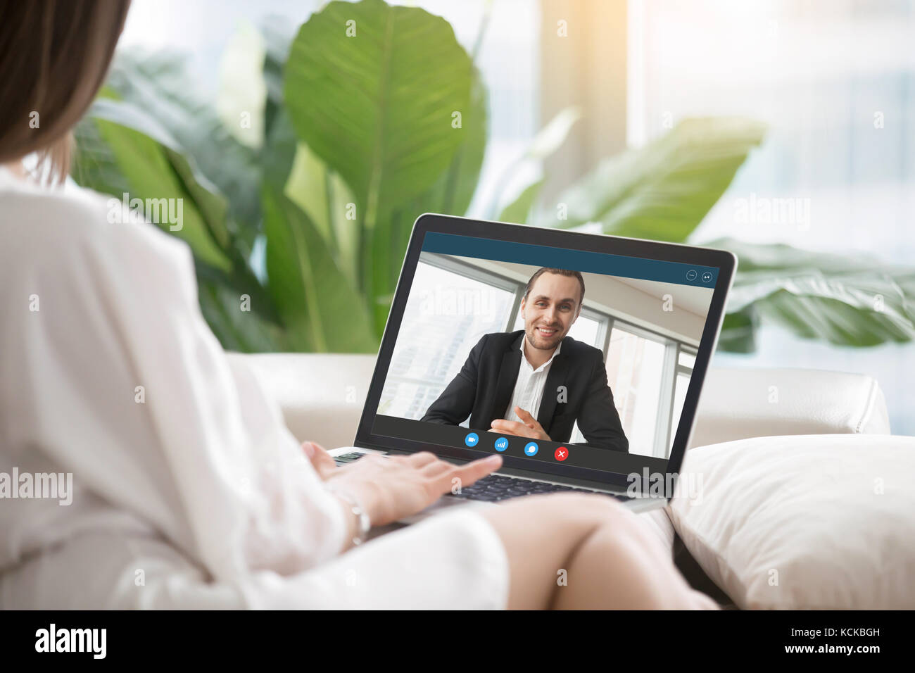 Young woman sitting on sofa communicates with man in formal suit via ...