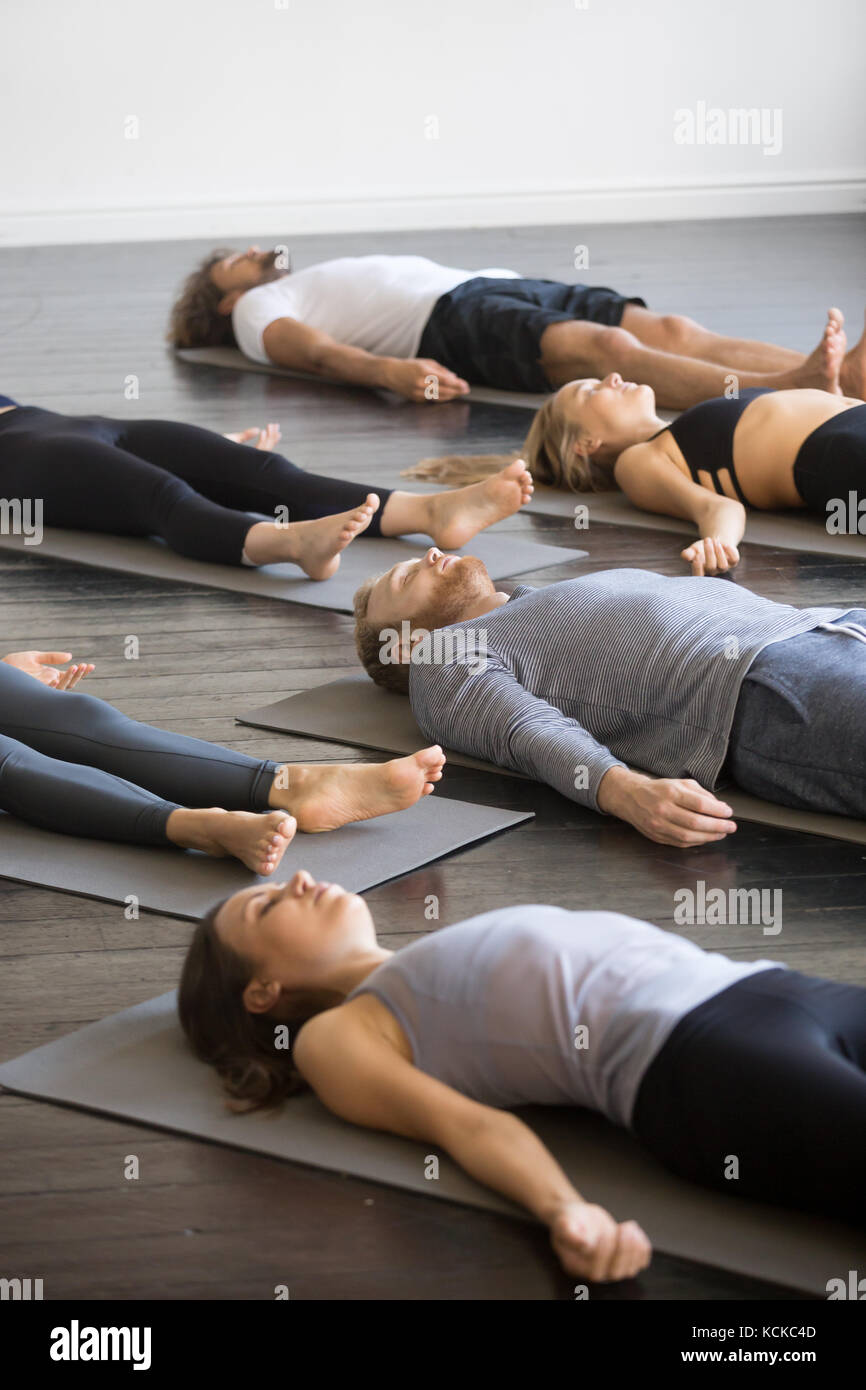 Group of young sporty people practicing yoga lesson with instructor in ...