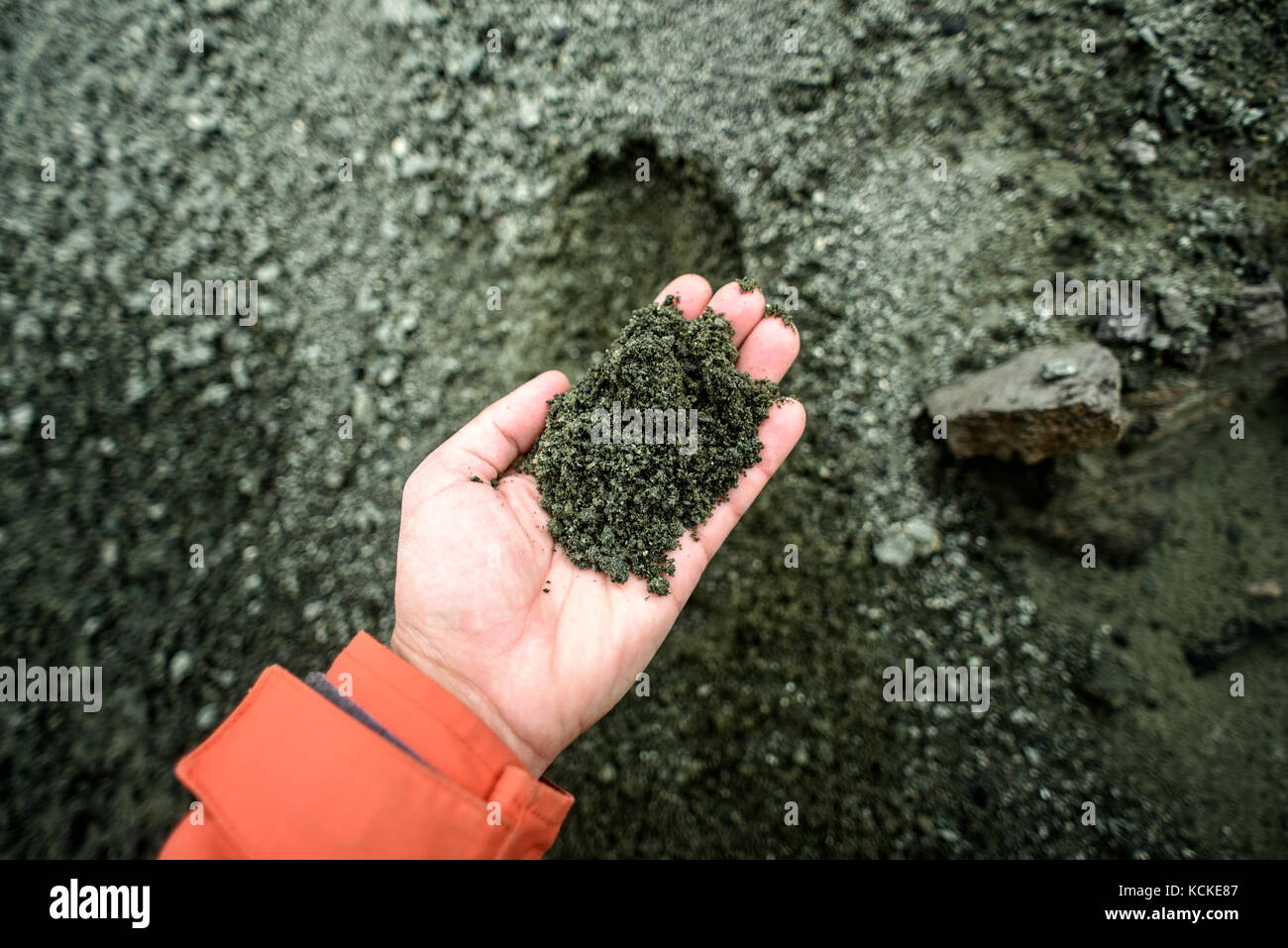 Female hand holding clump, volcanic dust in the mountains of Iceland ...