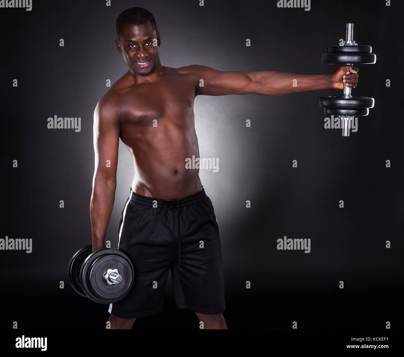 Portrait Of Young African Man Working Out With Dumbbells On Black ...