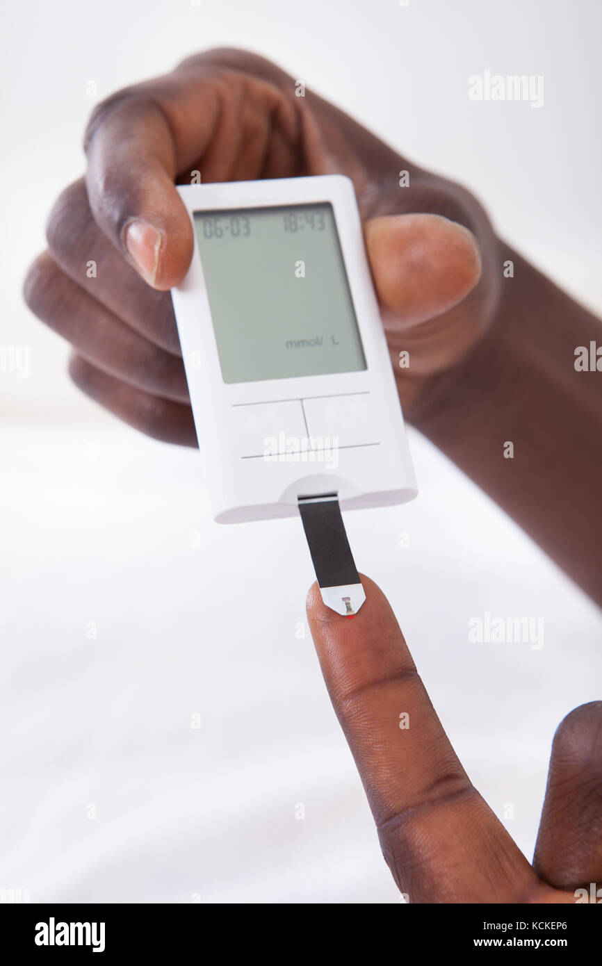 Close-up Of Hand Holding Glucometer Over White Background Stock Photo ...