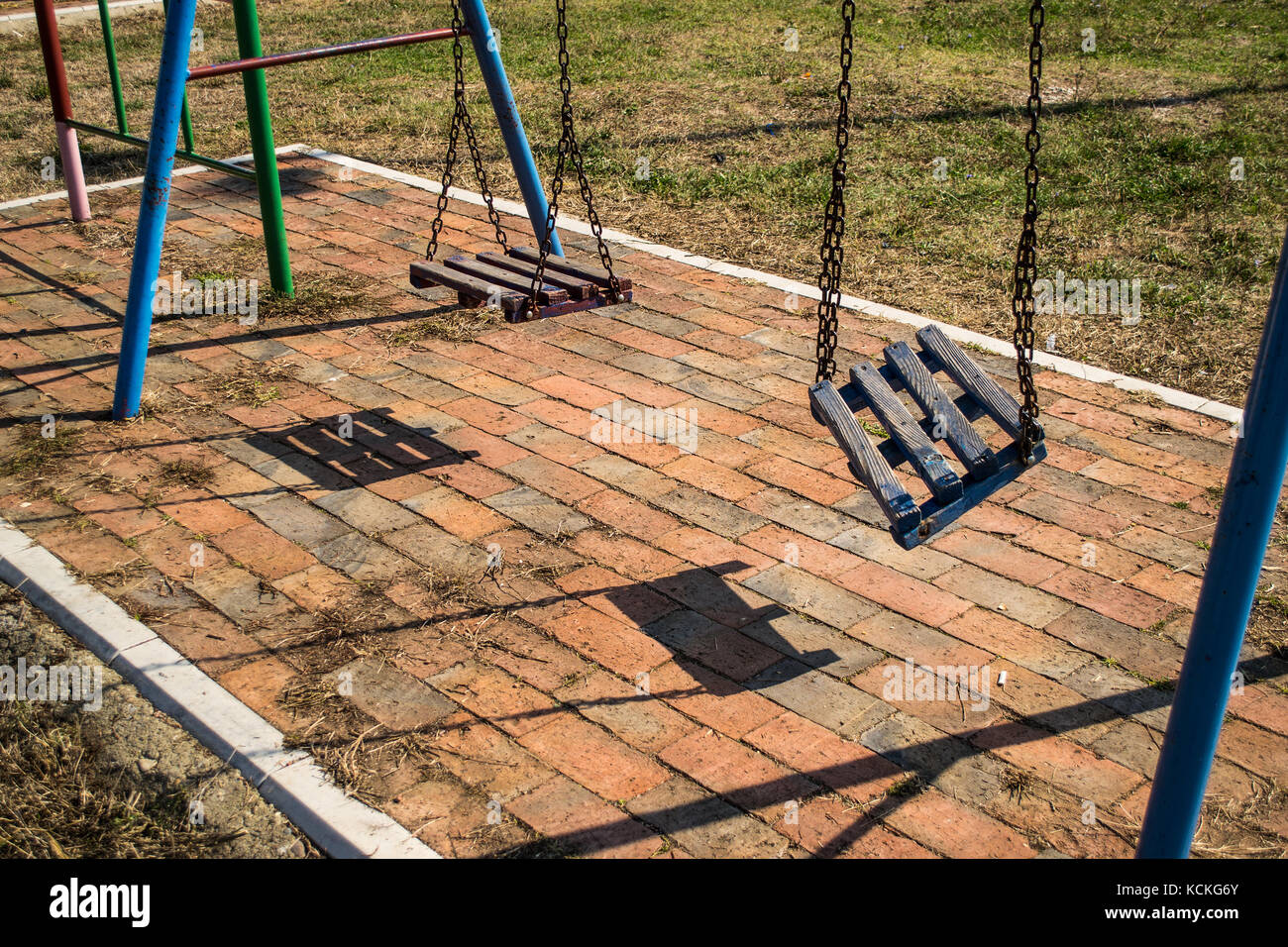 Broken swing in school yard Stock Photo - Alamy