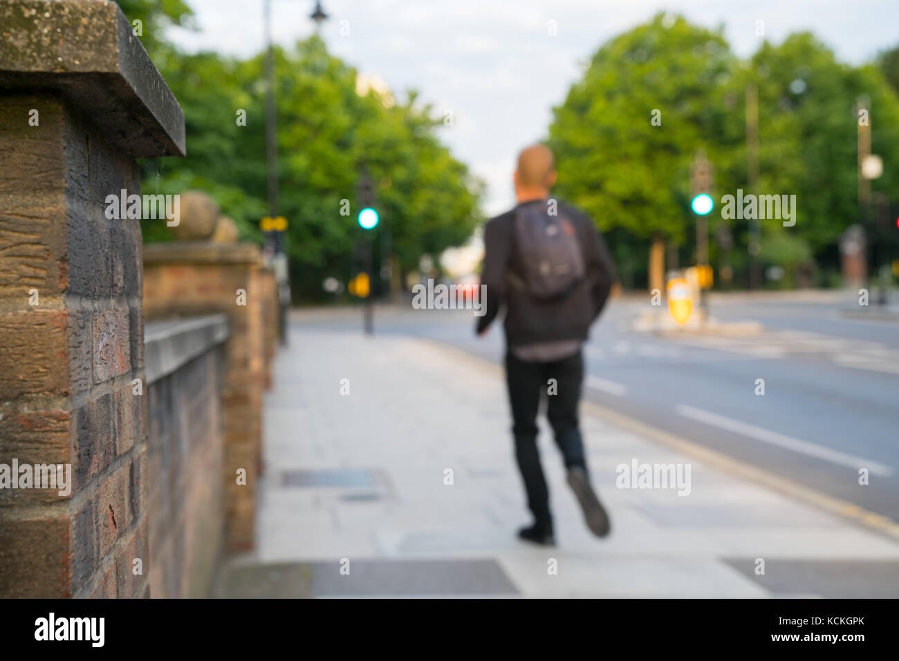Unrecognisable man walking toward traffic lights on city street ...
