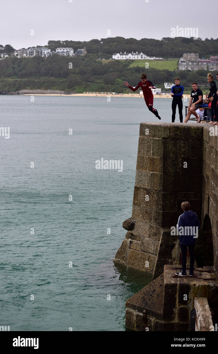 A young man jumping off the pier in St Ives harbour, Cornwall Stock ...