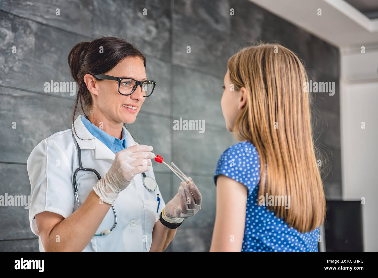 Female pediatrician using a swab to take a sample from a patient's ...