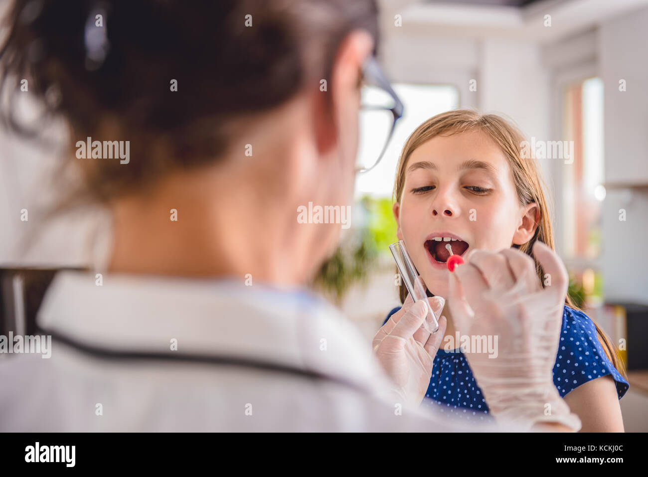Female pediatrician using a swab to take a sample from a patient's ...