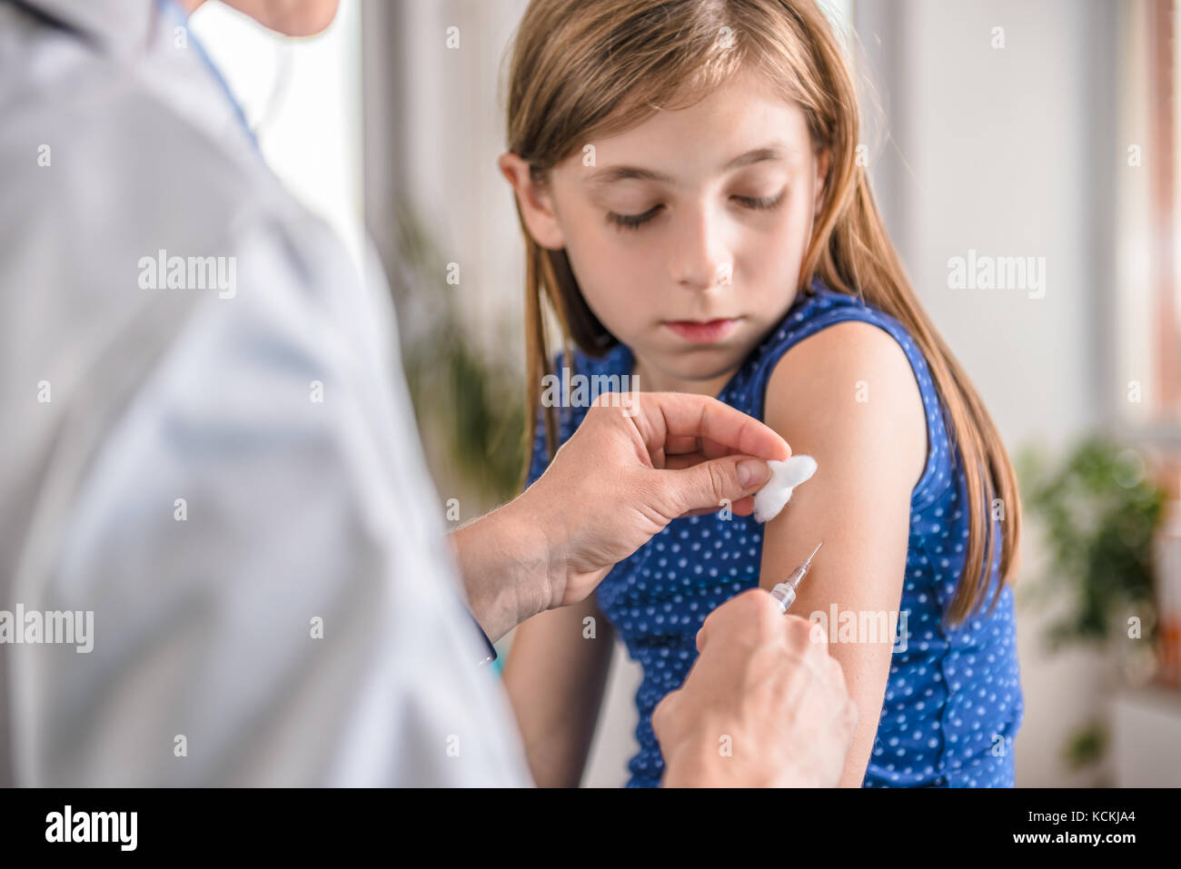 Pediatrics female doctor giving a young girl a vaccine shot in the arm ...