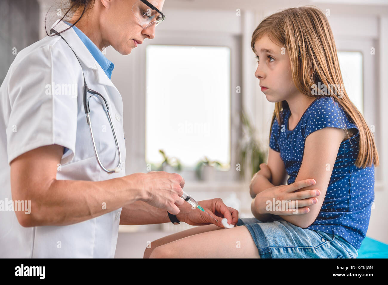Pediatrics female doctor giving a young girl a vaccine shot in the leg ...