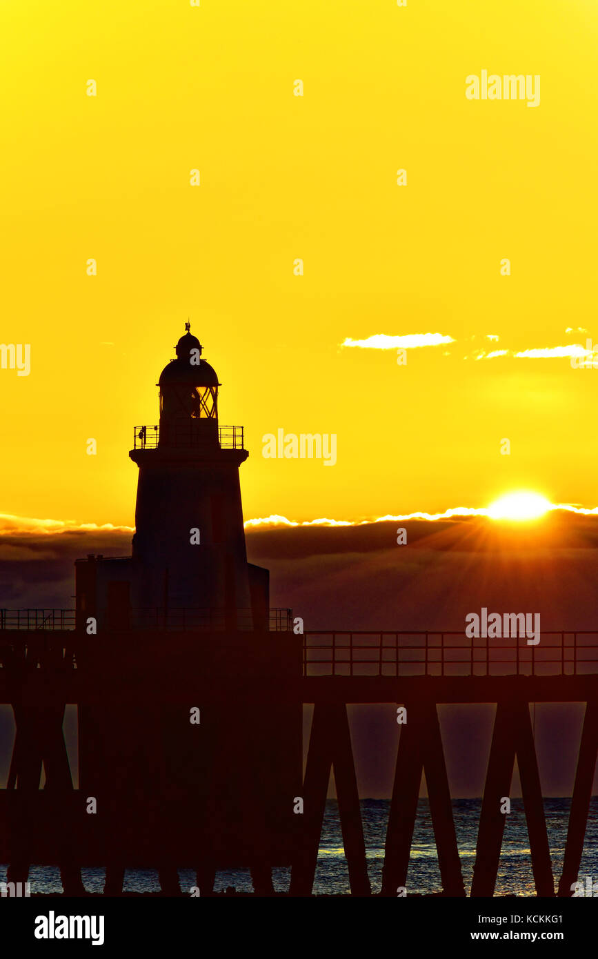 Blyth pier and lighthouse at sunrise with sun just peeking over the ...