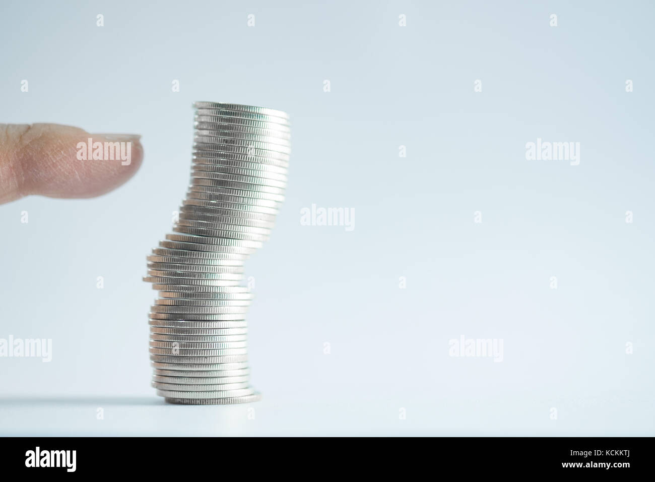 Finger pushing a stack of coins, column of coins falls , business ...