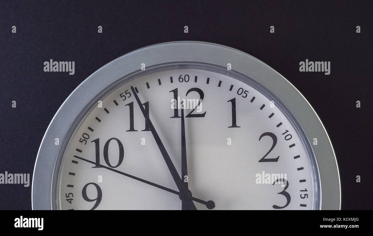 Simple round wall clock on a black background Stock Photo - Alamy