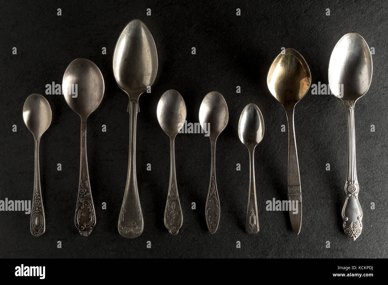 Different spoons on a black stone top view horizontal Stock Photo - Alamy