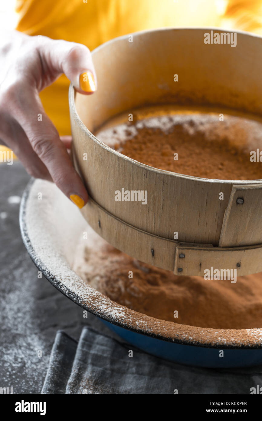 Sifting cocoa into a bowl with flour close-up vertical Stock Photo - Alamy