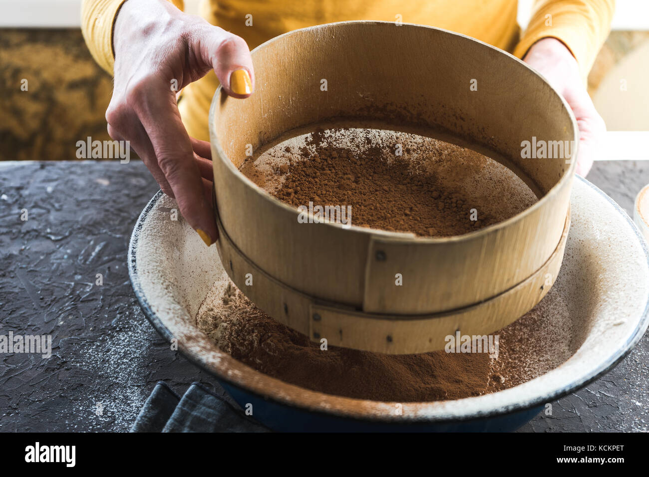 Sifting cocoa into a bowl with flour view from the side horizontal ...