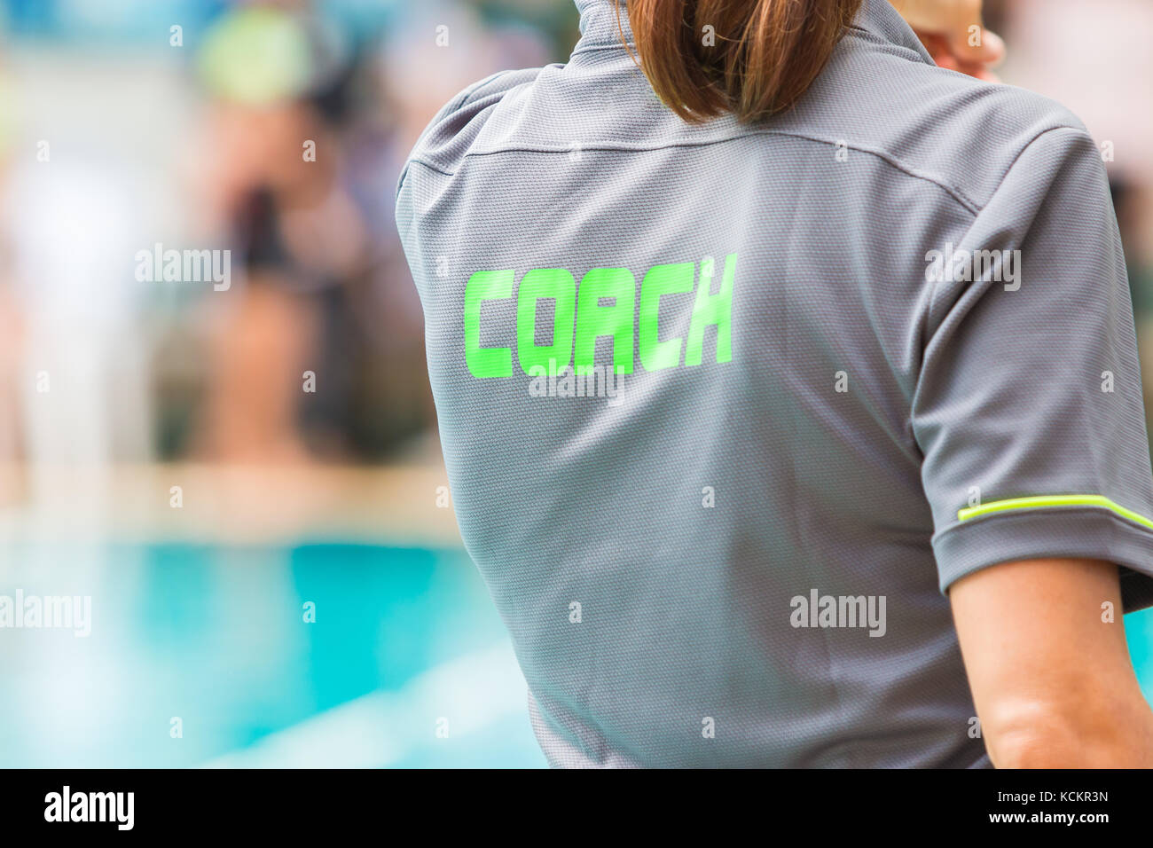 back of a coach's grey shirt with the green word Coach written on it ...