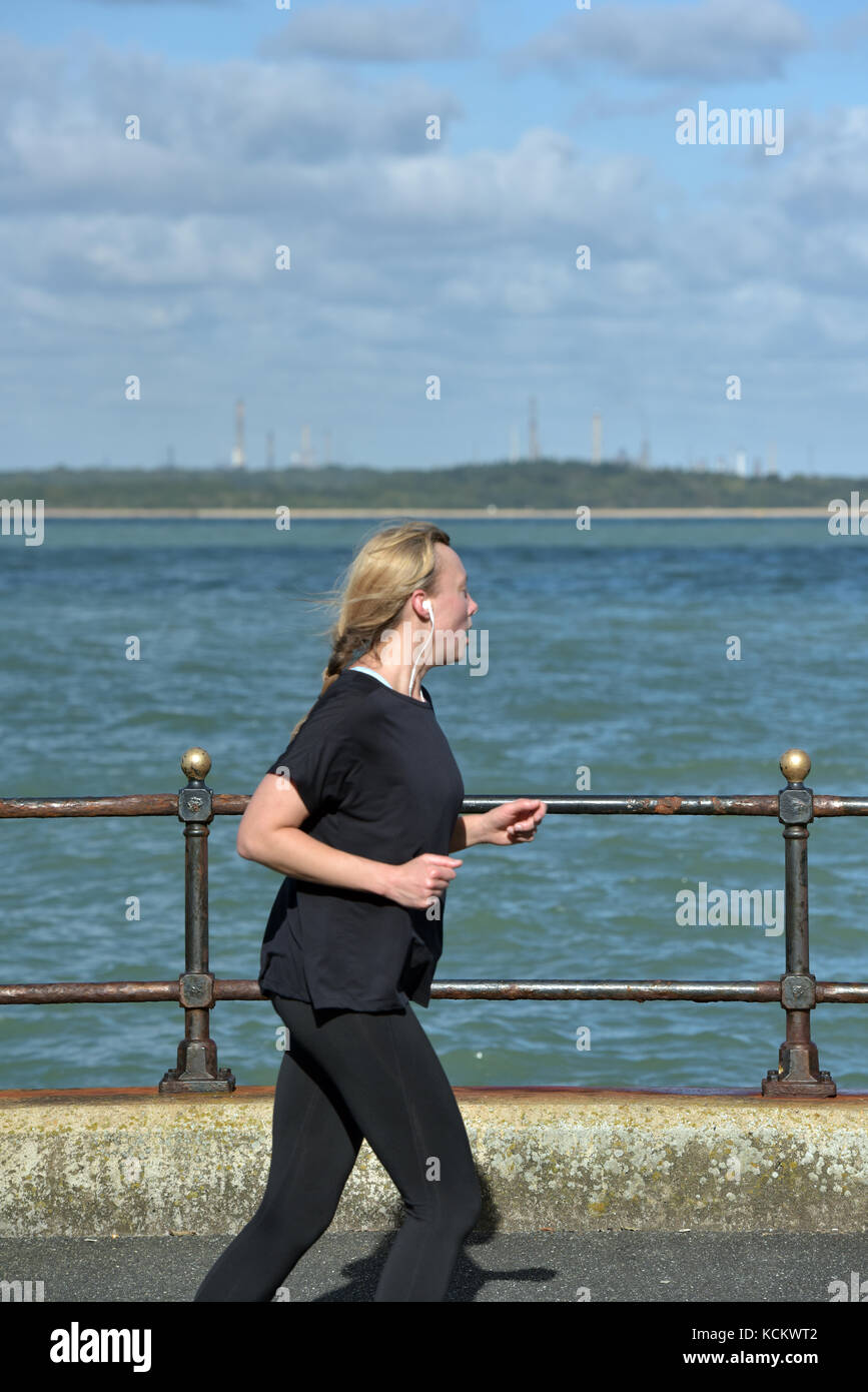 a young woman or lady running along the sea front in black running ...