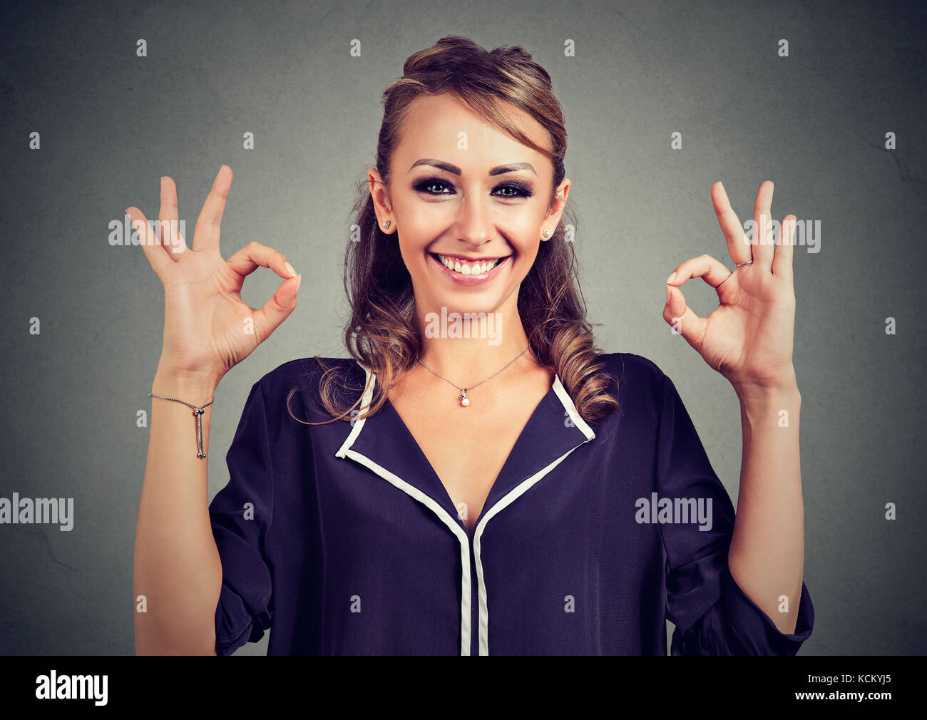 Cute playful woman showing two ok signs over gray background Stock ...