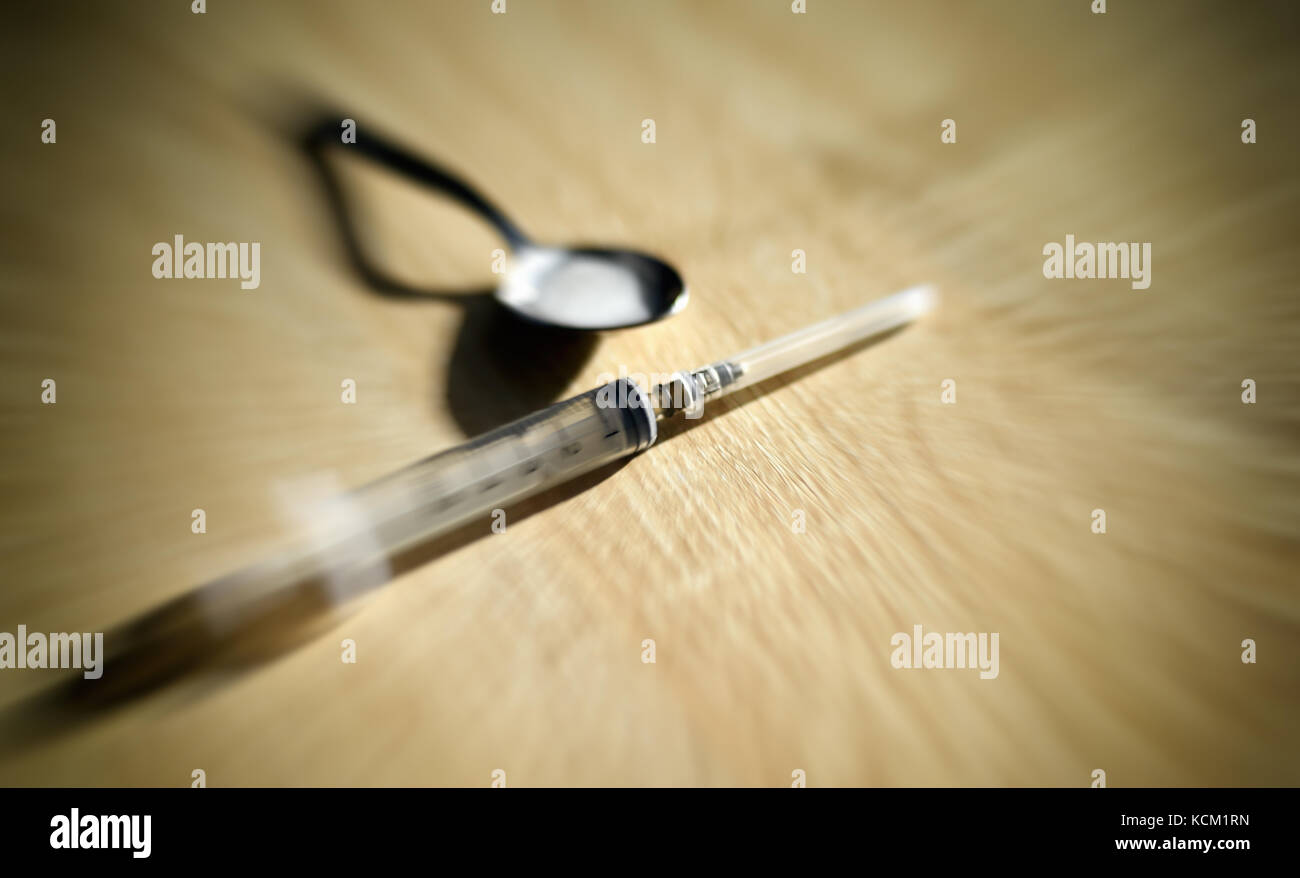 Silver spoonful of heroin opiate and an unused hypodermic needle ...