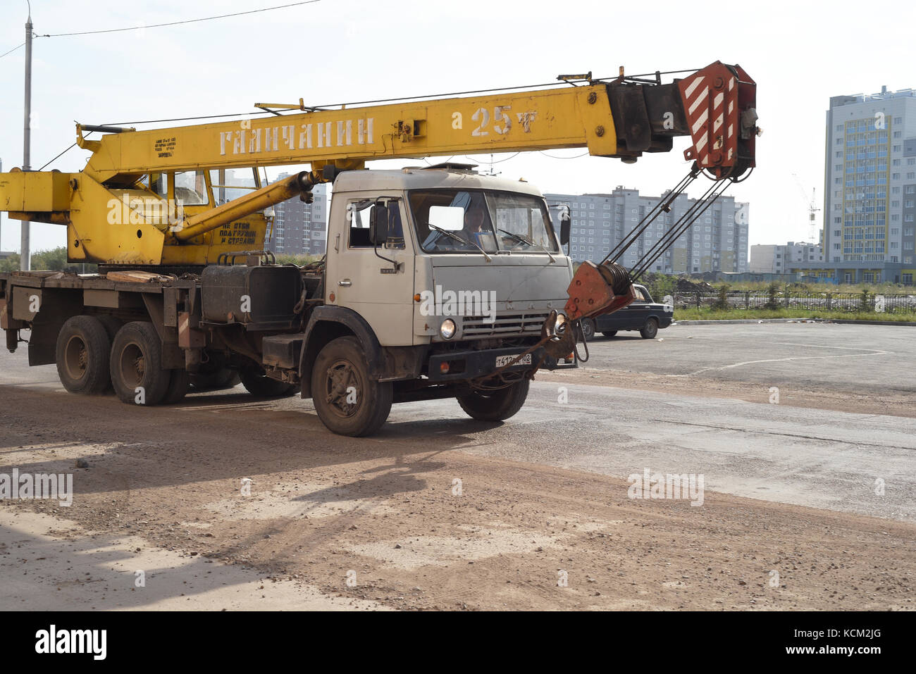 Old aged Kamaz vehicle with crane attachment moves along an empty road ...