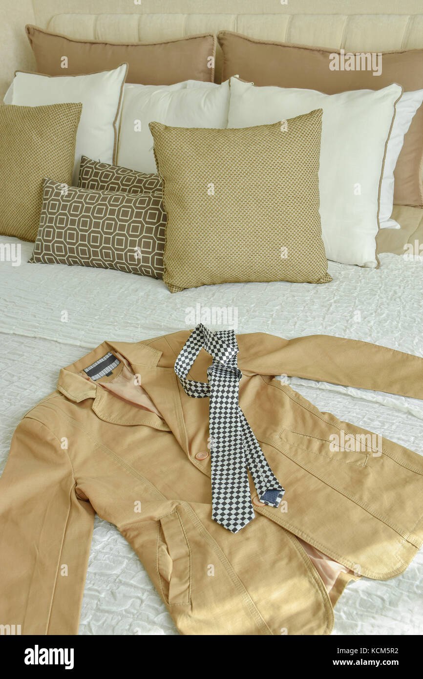 Suit and necktie on bed with brown and beige pillows Stock Photo - Alamy