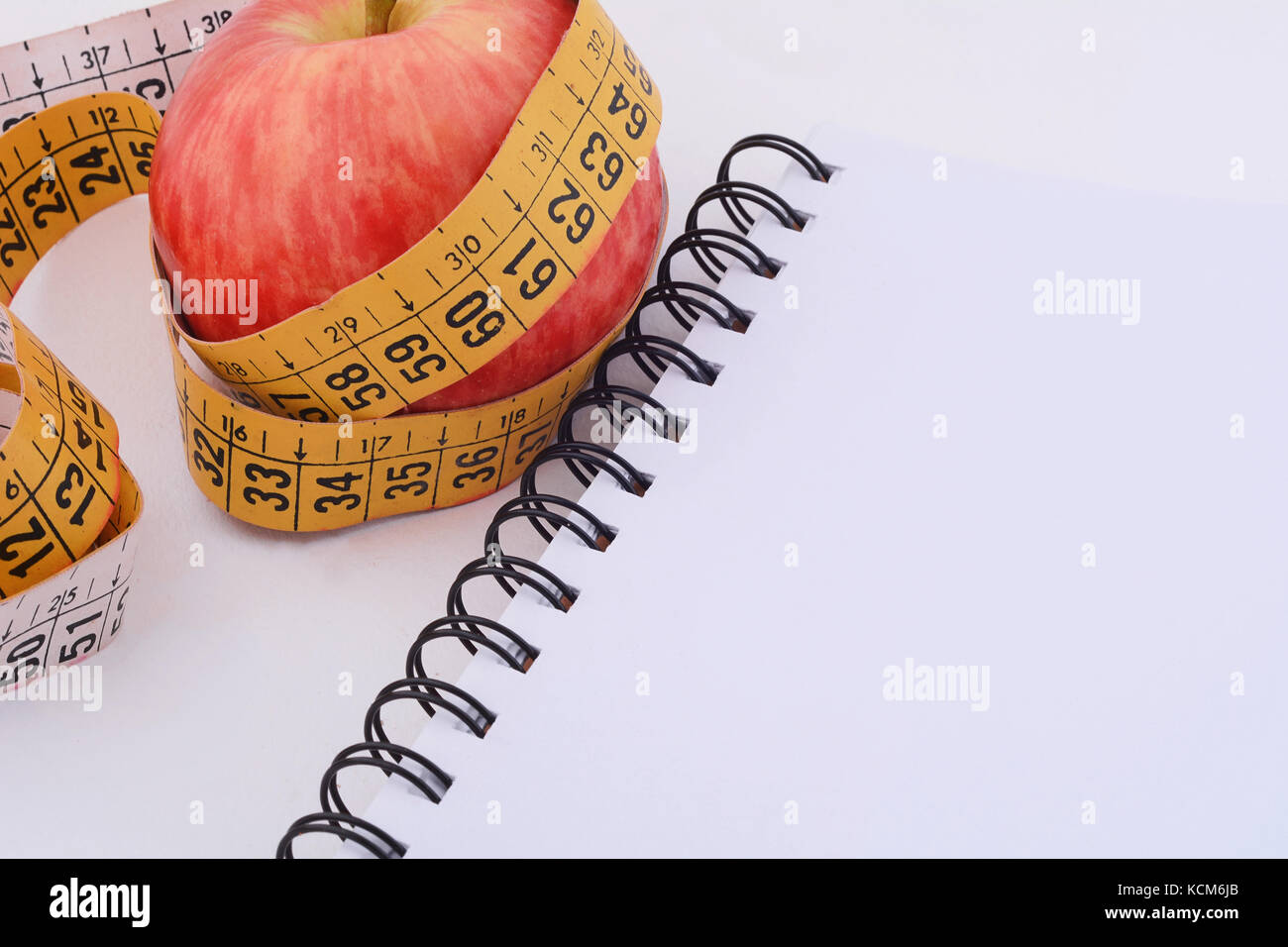 An apple and measuring tape on notepad. Healthy food concept. Isolated ...