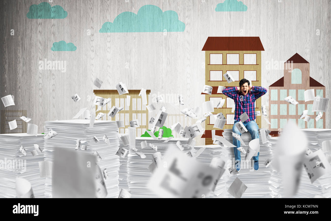 Young man sitting on pile of paper documents Stock Photo - Alamy