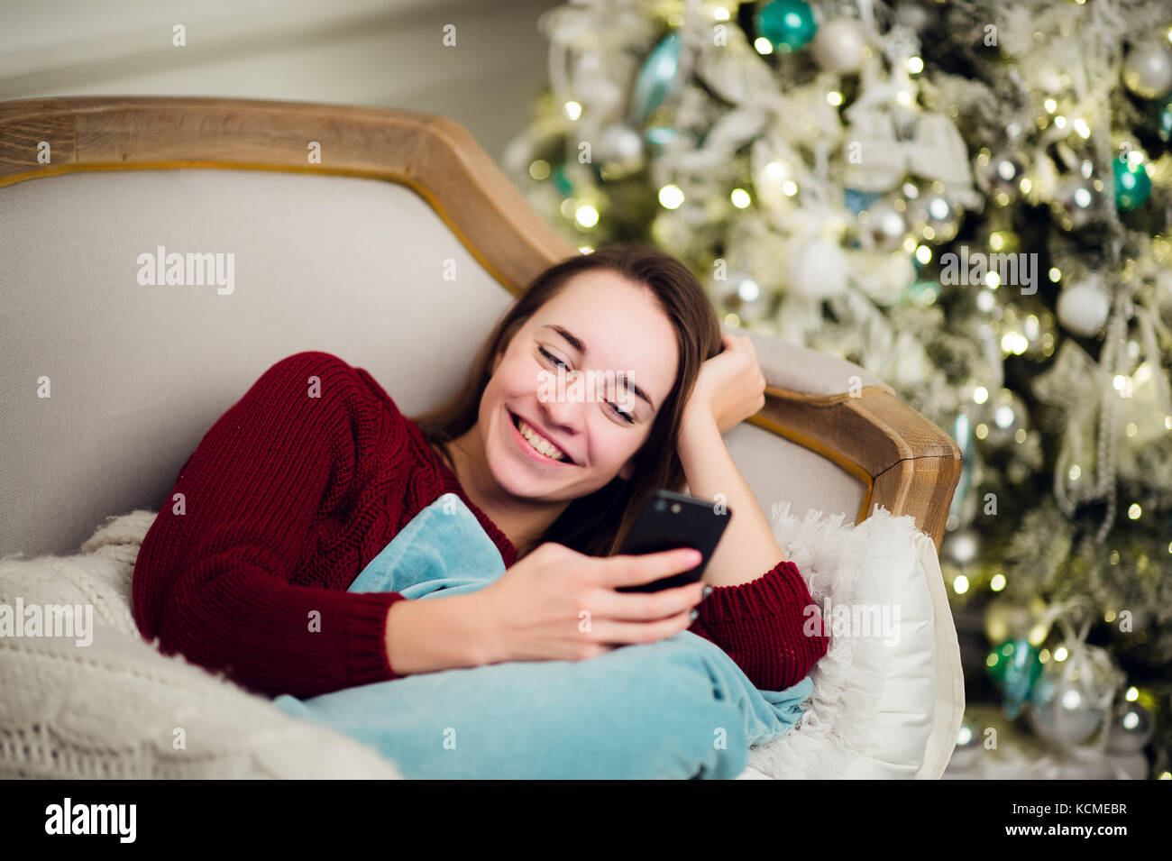 Young woman checking out her text messages on mobile phone as she liyng ...