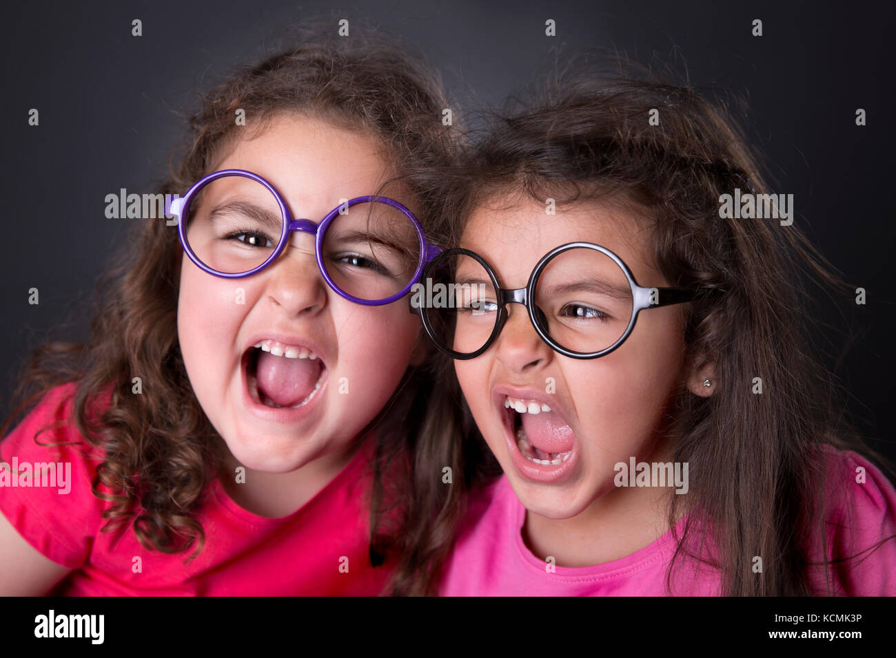 Portrait of pair of cute girls screaming at camera. Studio shot. Black ...