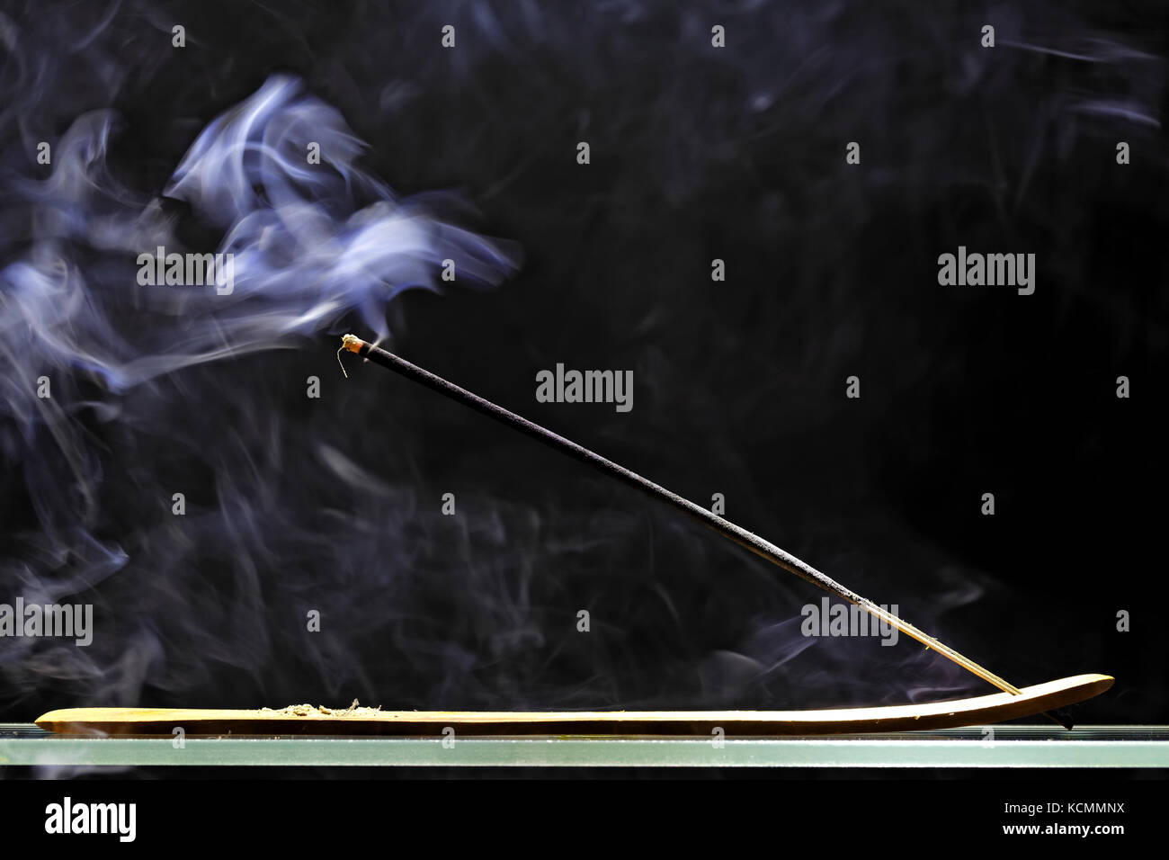 Incense stick smolders and emits intensive smoke on black background ...