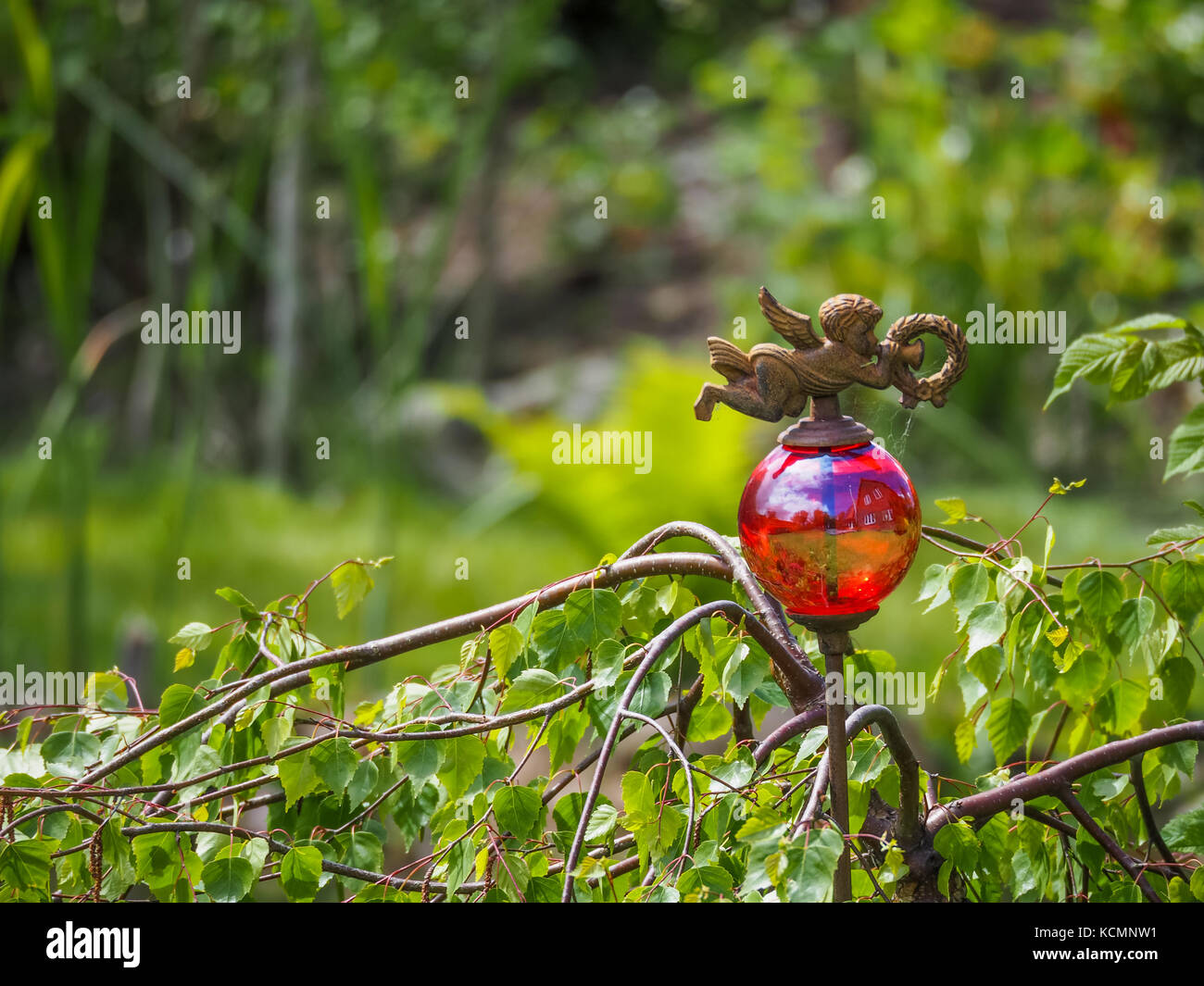 Red seethrough glass ball on rusty stick with decorative angel and ...