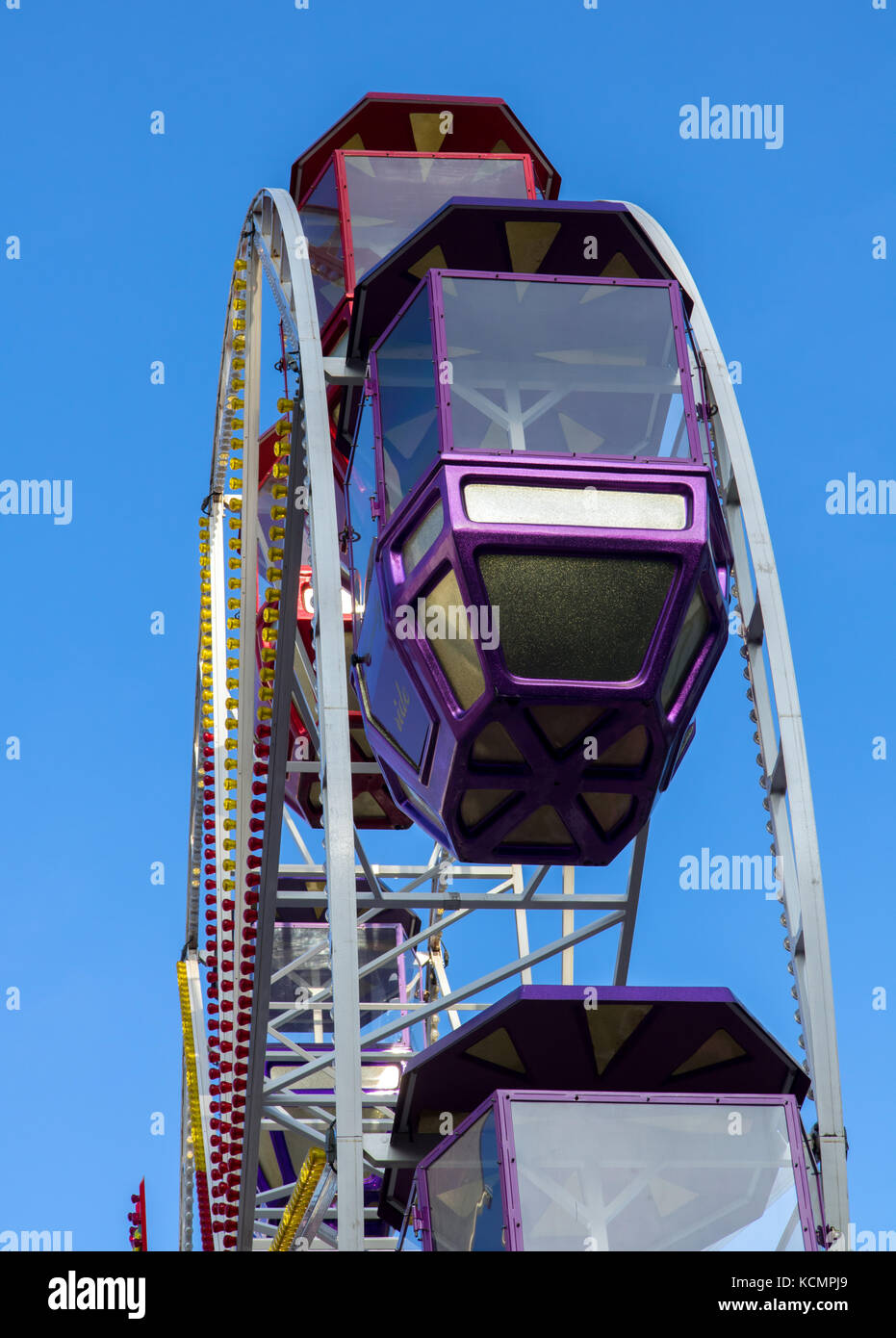 Small cabin of a ferris wheel against a blue sky. Empty gondolas of the ...
